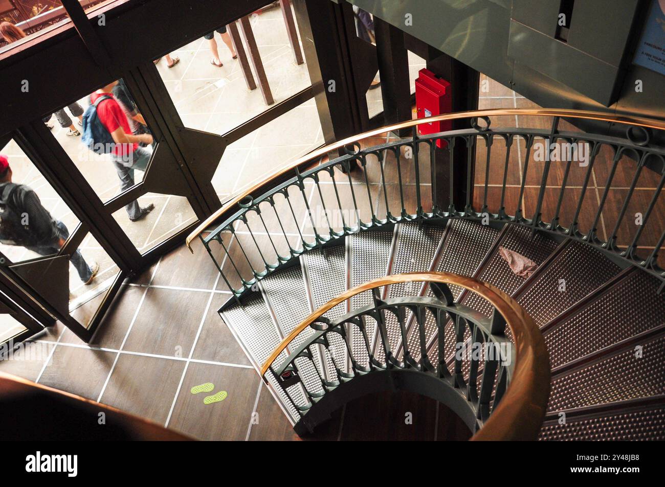 Curved metal staircase in a modern building, with people walking by ...