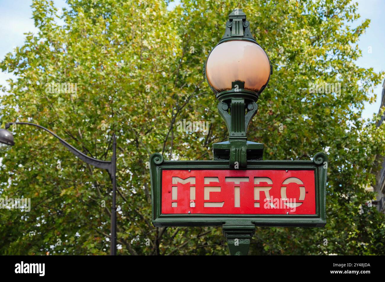 Paris Metro sign amid lush green trees on a bright day, representing ...