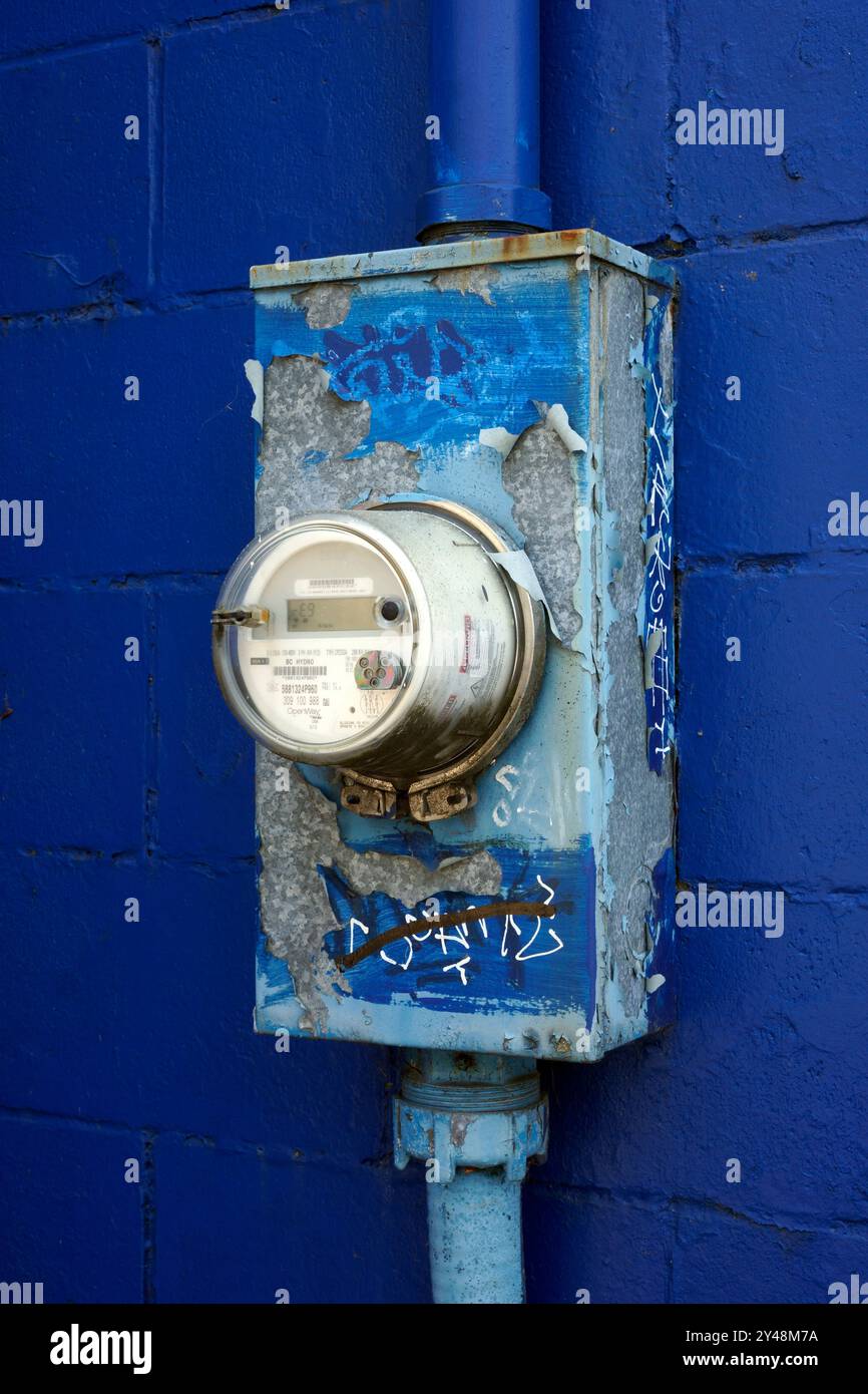 Electric meter with urban graffiti mounted on the blue wall of a ...