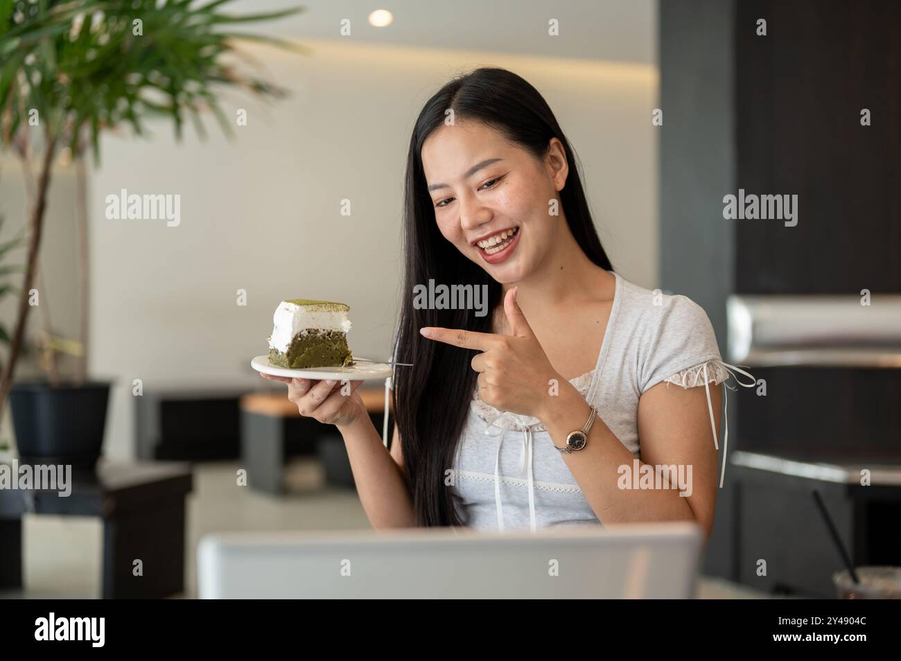 An attractive, happy Asian woman showing a yummy matcha cake to her ...