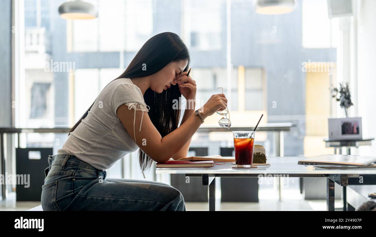 A side view of a beautiful, stressed Asian woman sitting in a modern ...