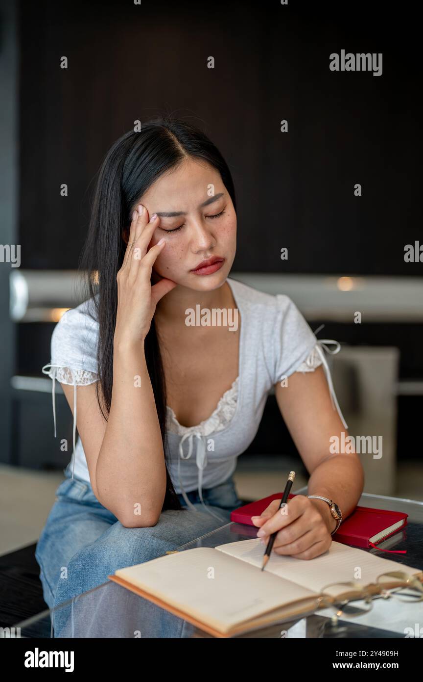 A stressed, thoughtful Asian woman feeling headache and eye strain ...