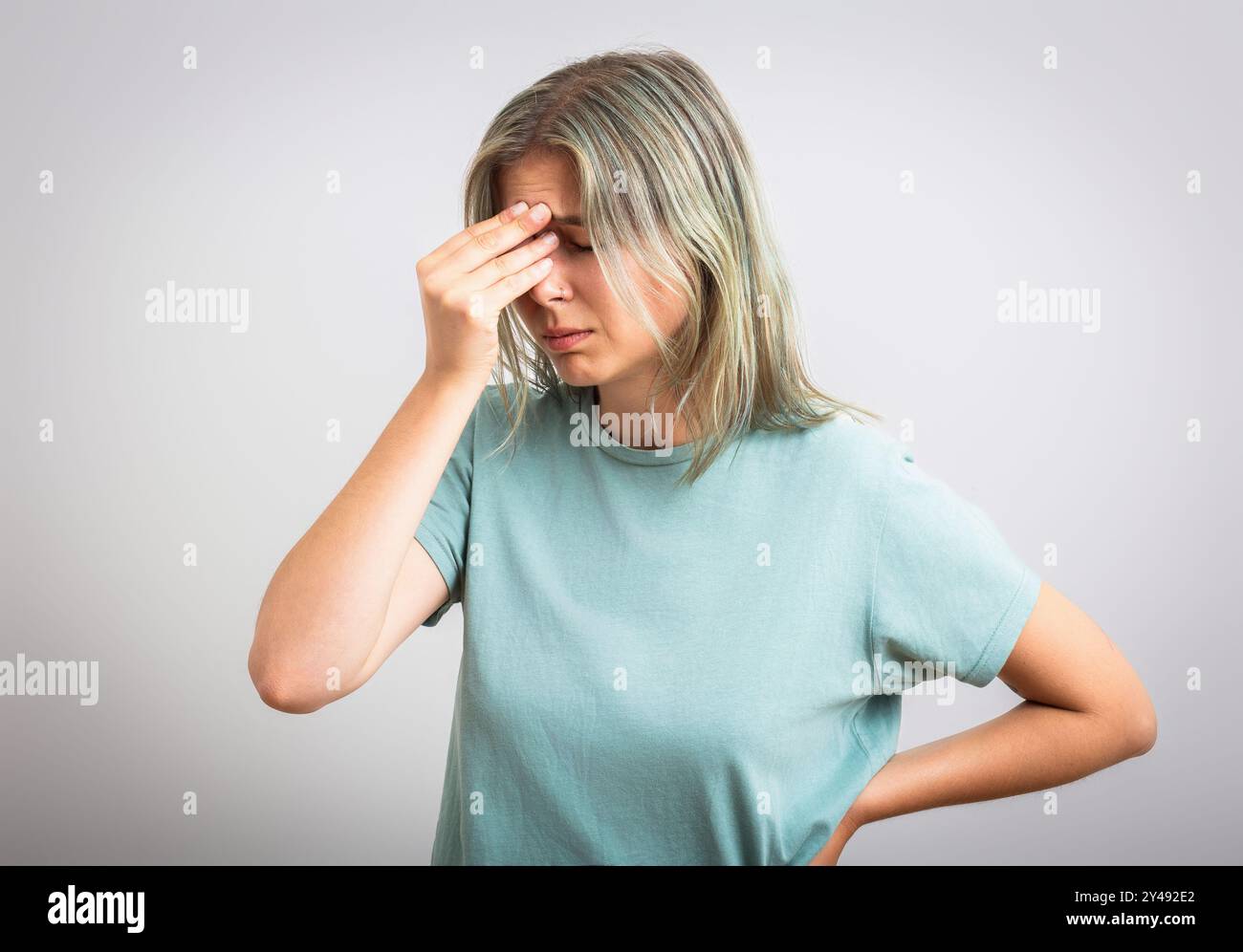 Young woman rubs her nose because of stress, pain, problem. Isolated on ...