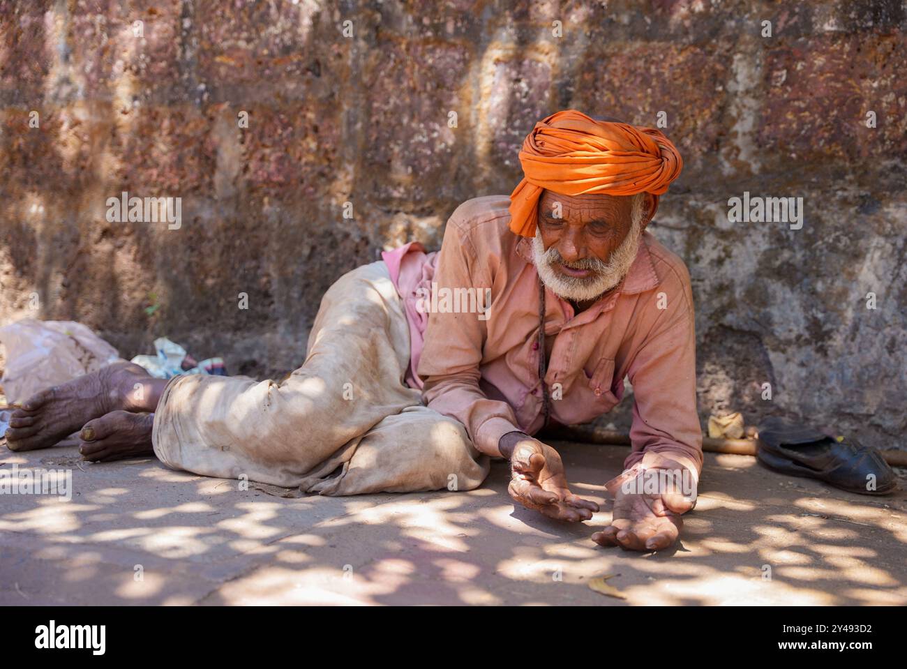 GOA, India - February 21, 2024: An old man in dirty clothes lies on the ...