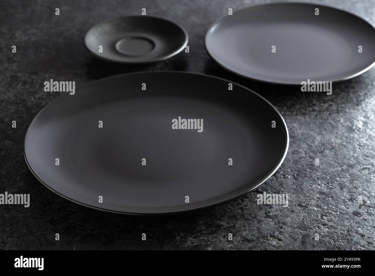 Empty black ceramic plates on a black stone table Stock Photo - Alamy
