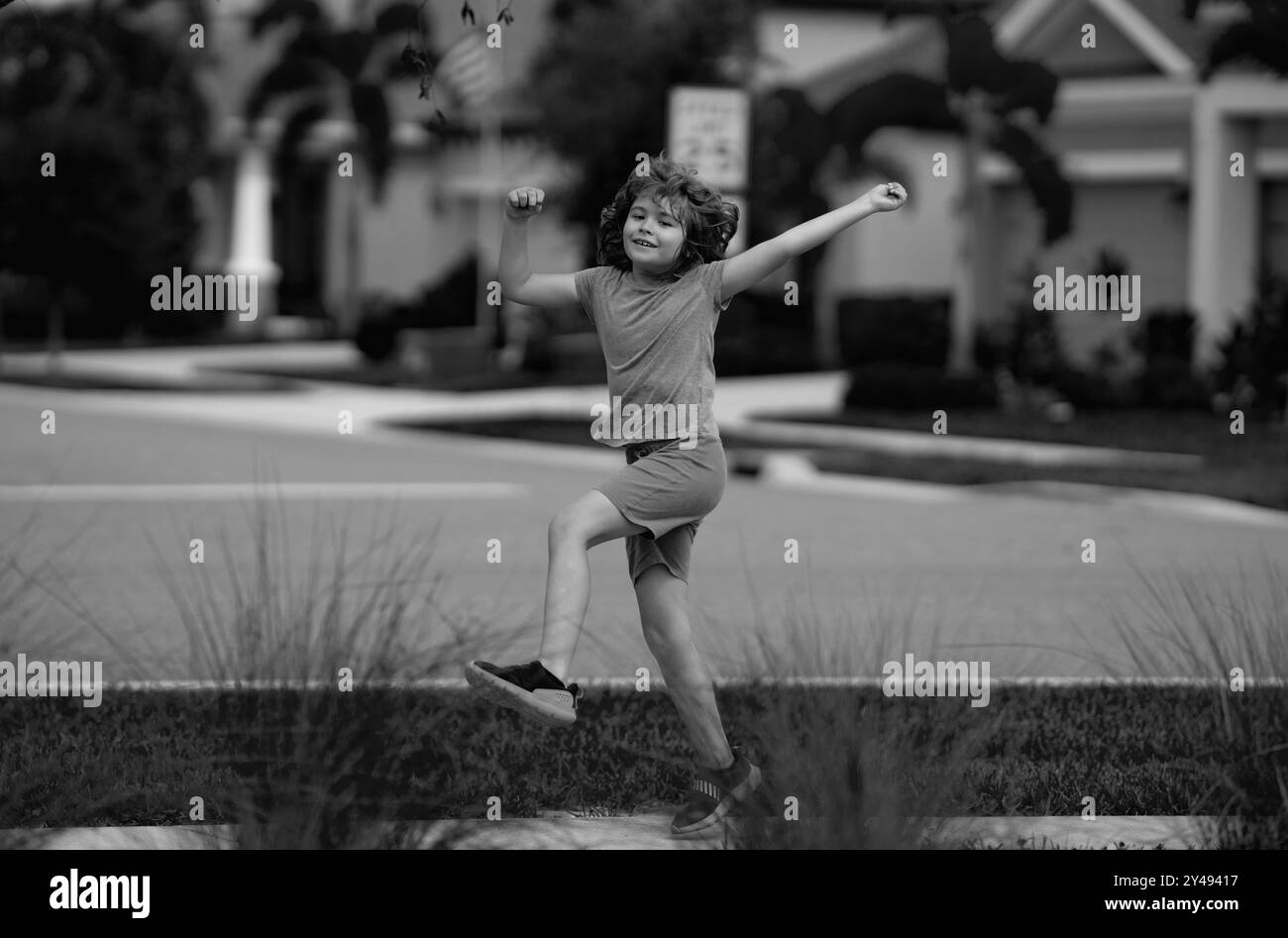 Cute kid boy running across american neighborhood street. Summer ...