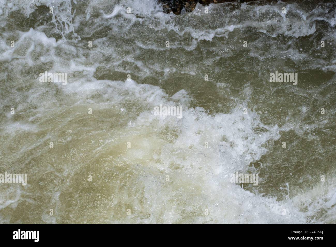 Close-up of foamy, turbulent water churning and swirling. The water is ...