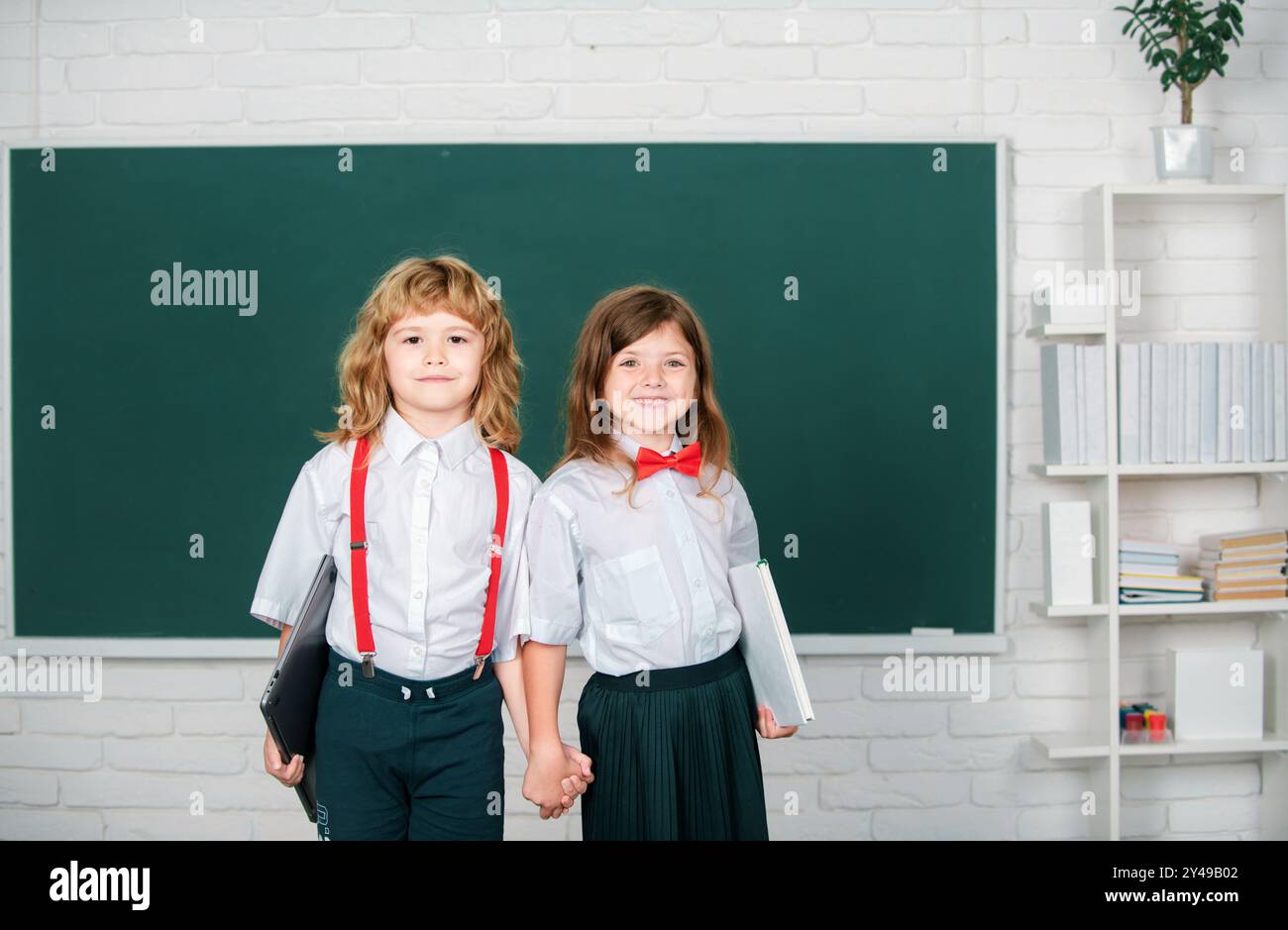 Portrait of two happy school kids studying in classroom at elementary ...