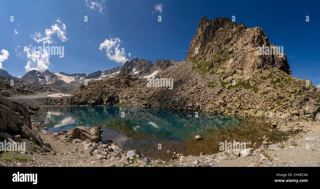 Clear mountain lake reflecting snow capped peaks in rugged alpine ...