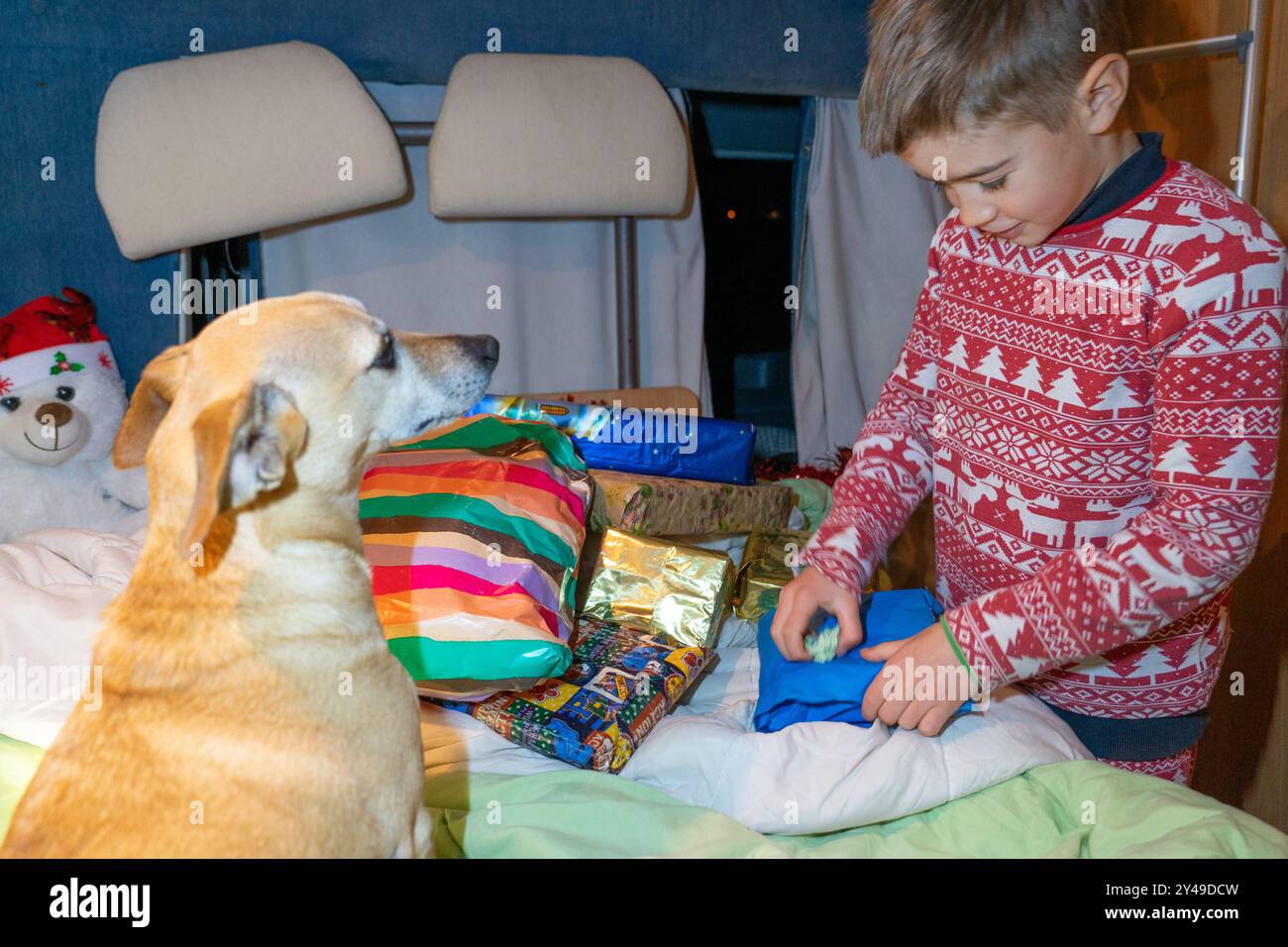Boy dressed as Christmas opening Santa Claus's gifts inside a motorhome ...