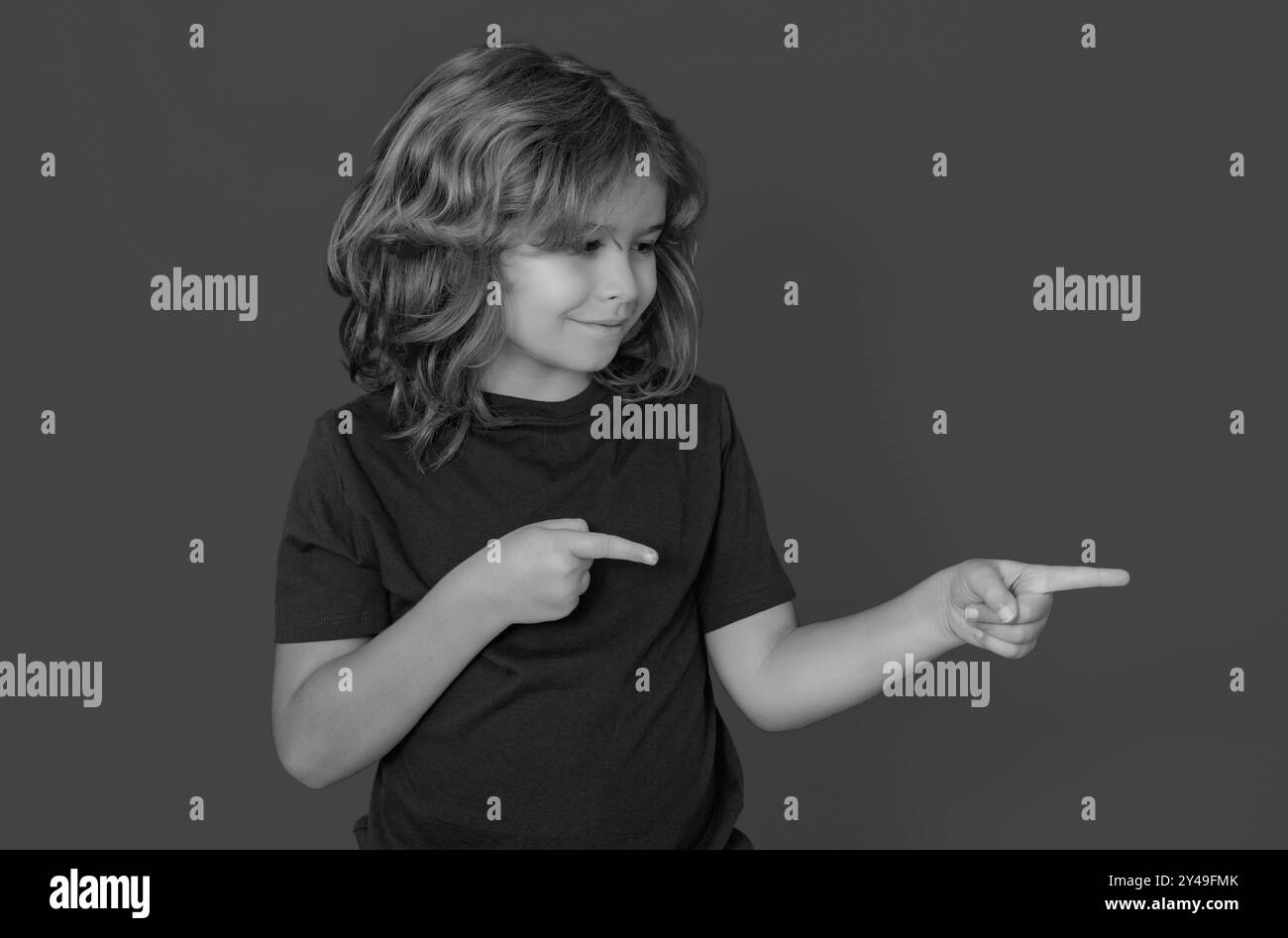 Child boy pointing finger away on yellow isolated studio background ...