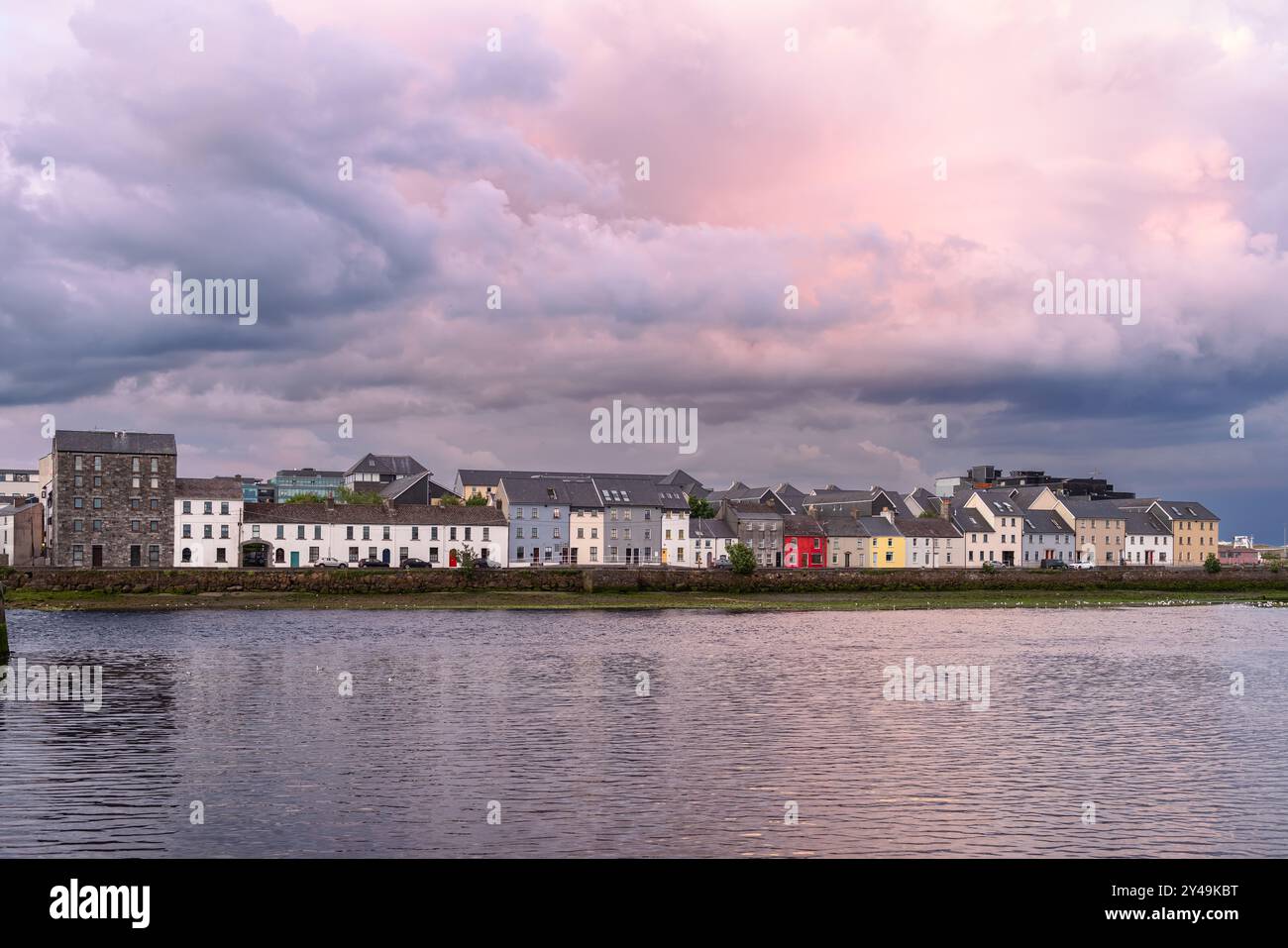 Waterfront of Galway City, Ireland, under a dramatic sunset sky with ...