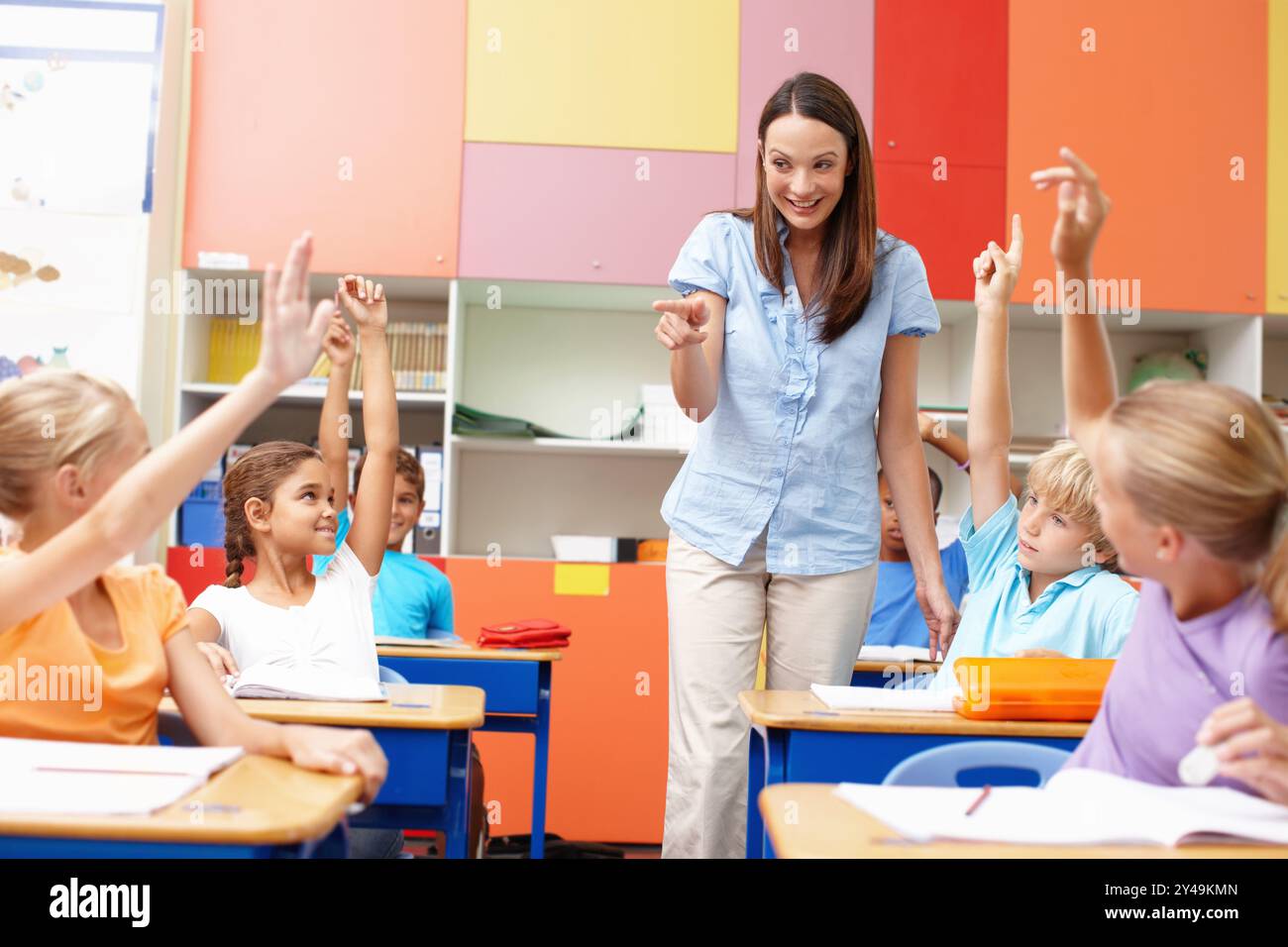 Woman, question and children with hands raised in class for education ...