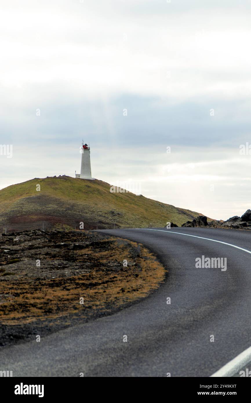 A road with a lighthouse in the distance. The road is empty and the sky ...