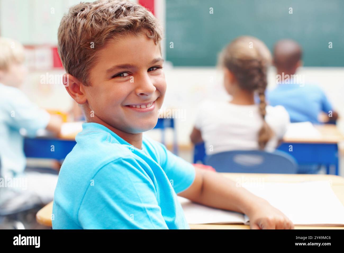 Smile, portrait and boy at desk in classroom for learning, growth and ...