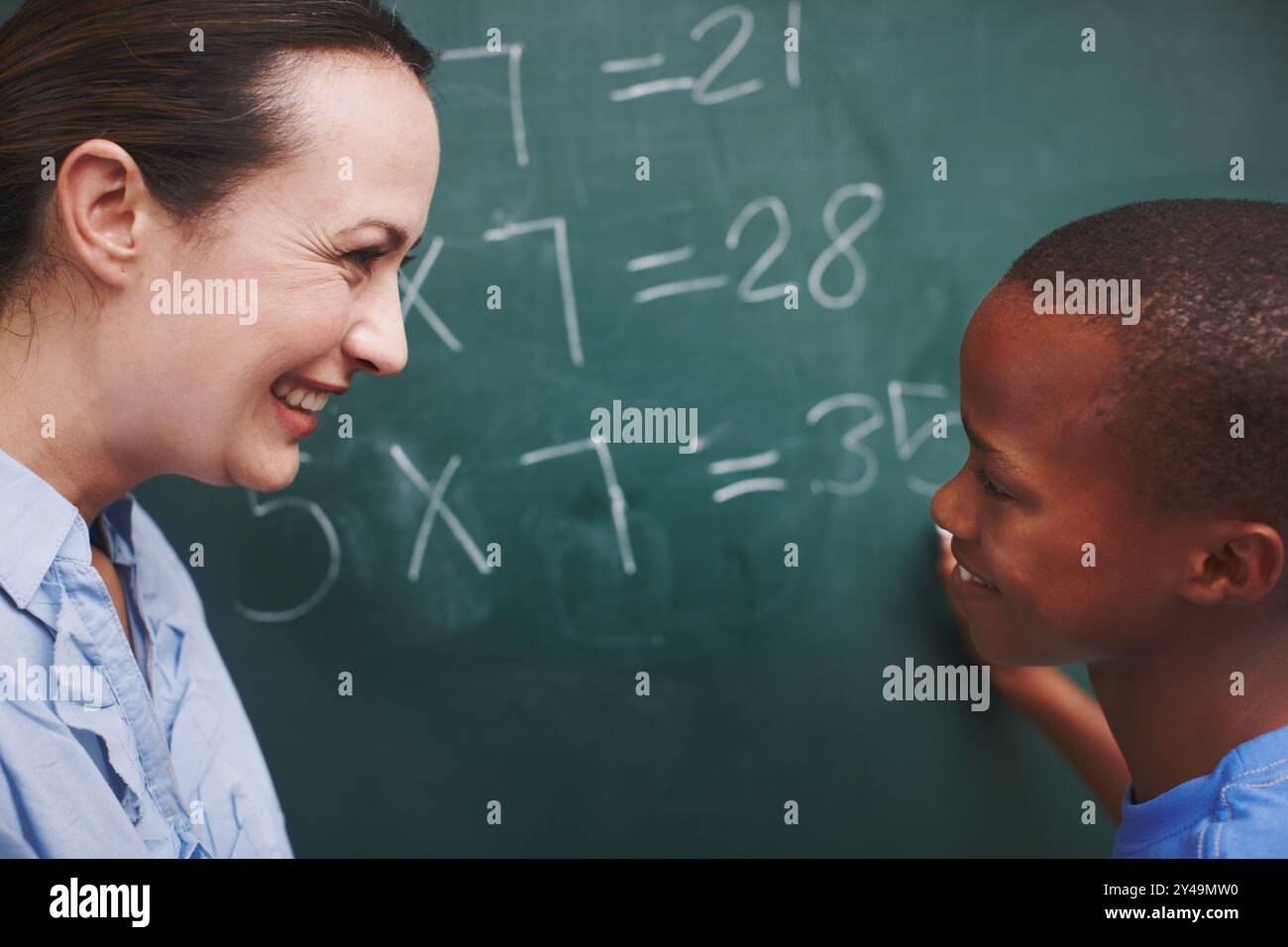Math, teacher and boy learning at chalkboard in classroom for solving ...