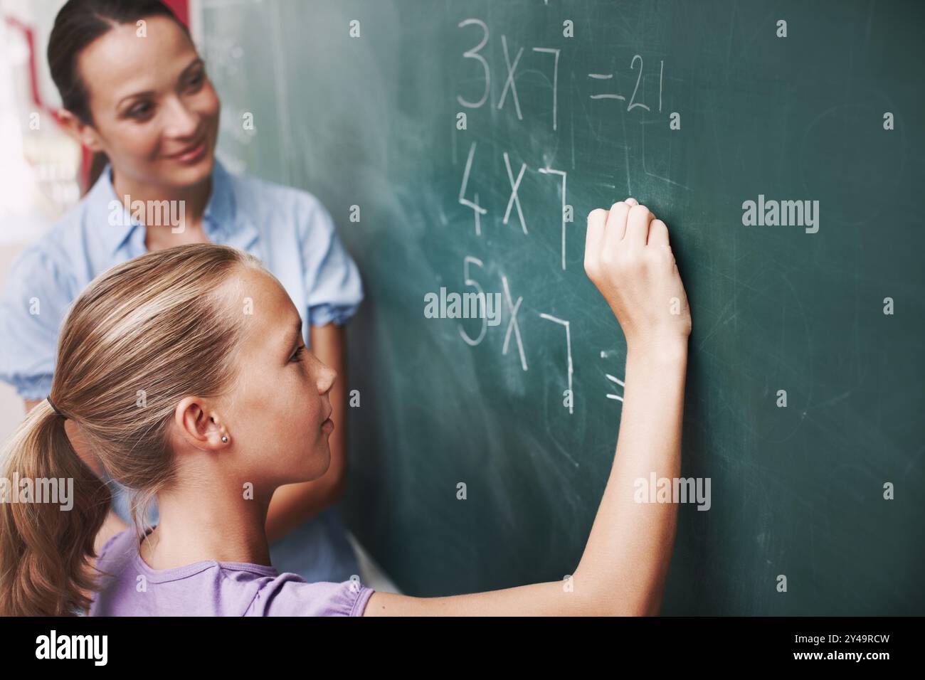 Math, teacher and student writing on chalkboard in classroom for ...
