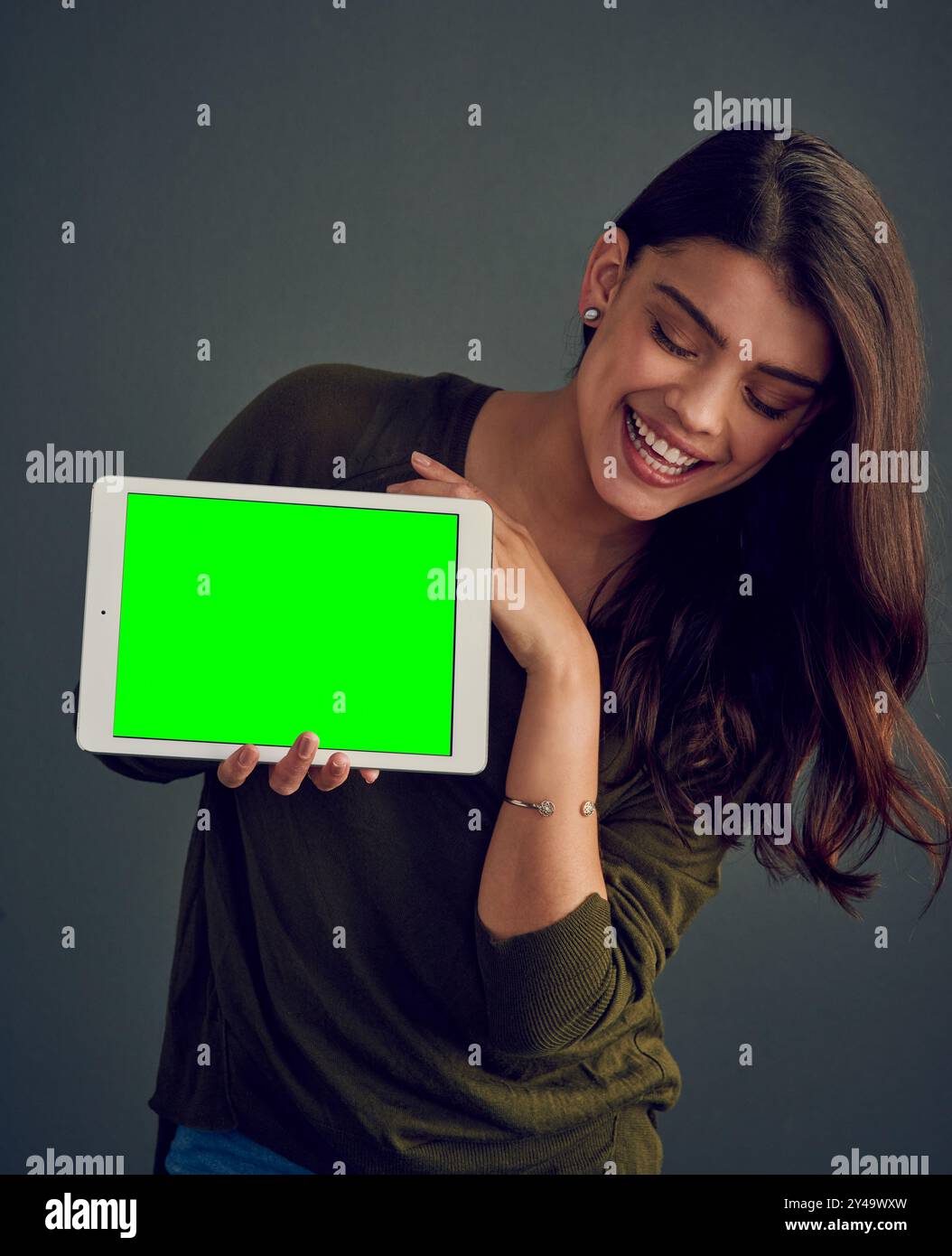 Woman, tablet and happy in studio with green screen, mock up space and promo by dark background ...