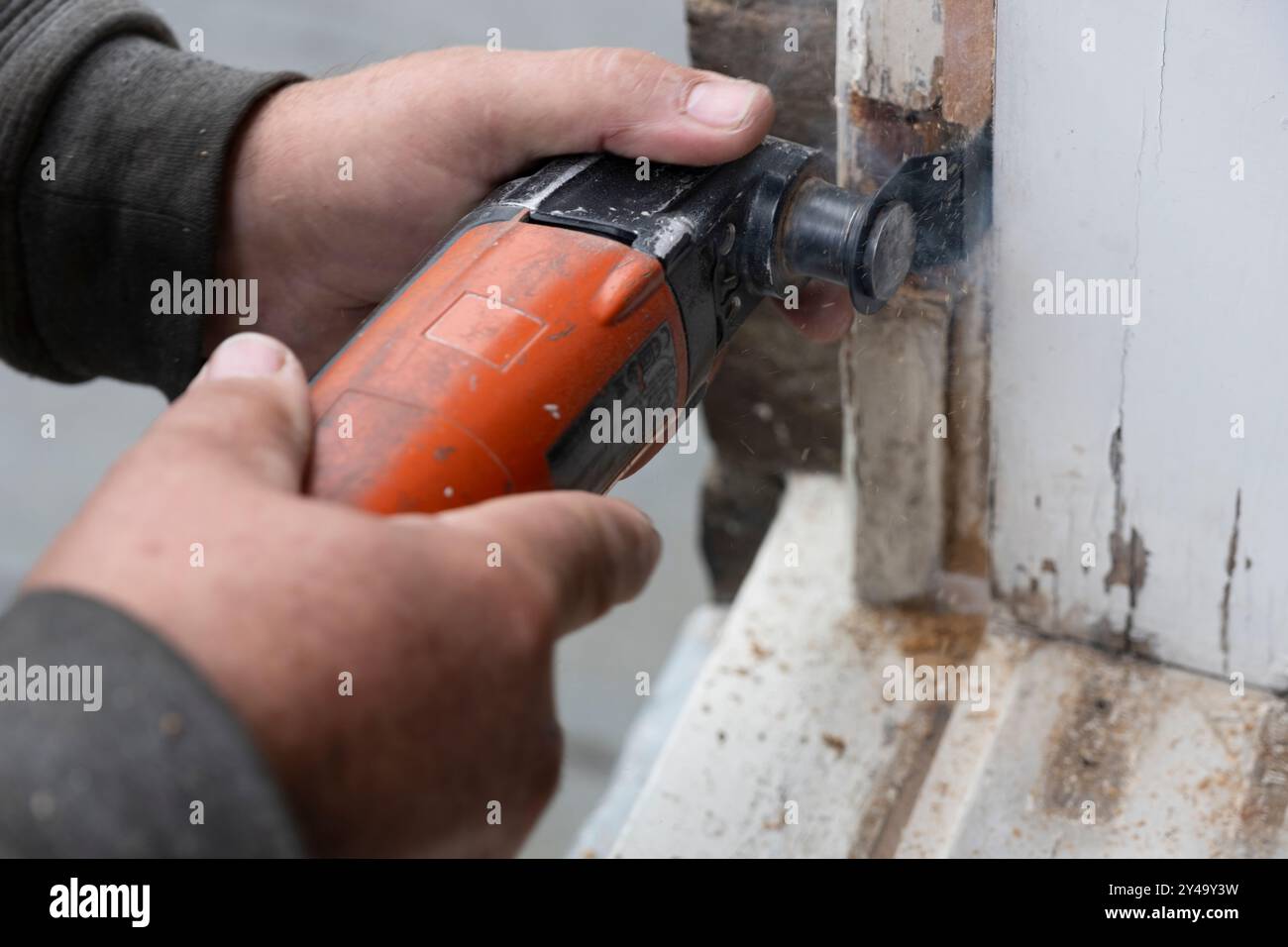 Carpenter cuts a piece of rotten wood from a window frame with an ...