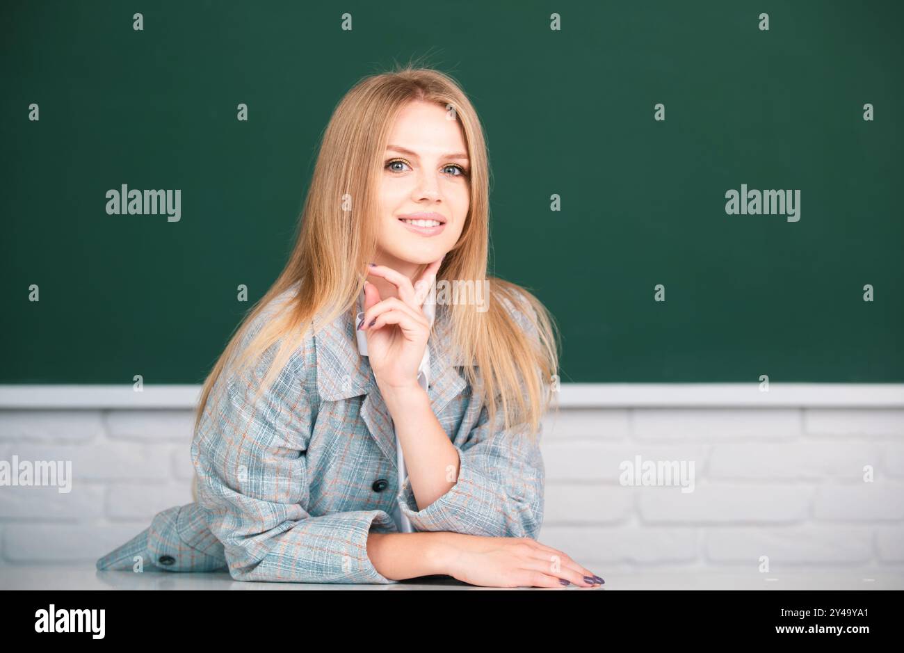 Portrait of smiling young college student studying in classroom ...