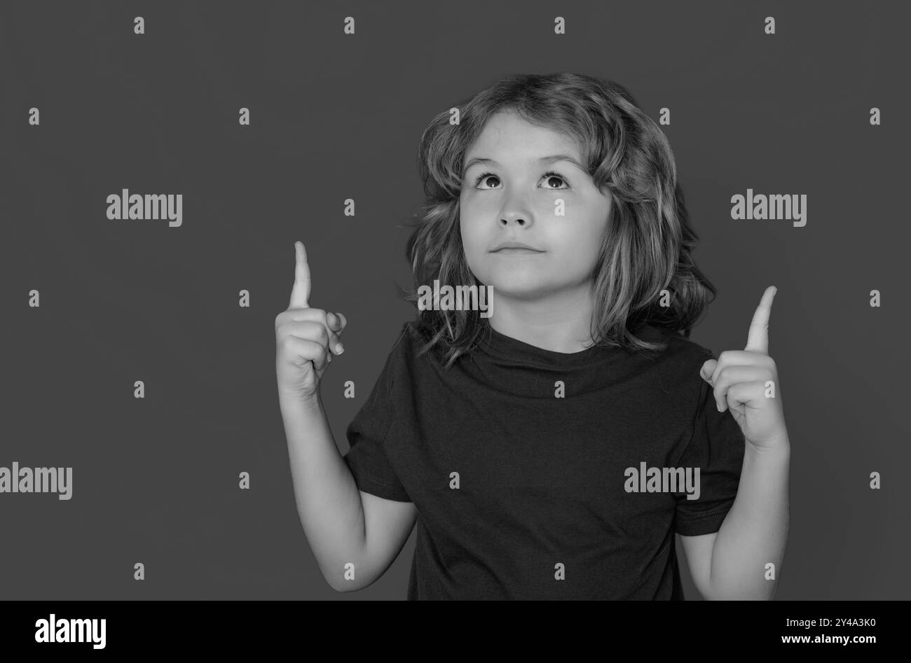Child boy pointing finger up on yellow isolated studio background ...