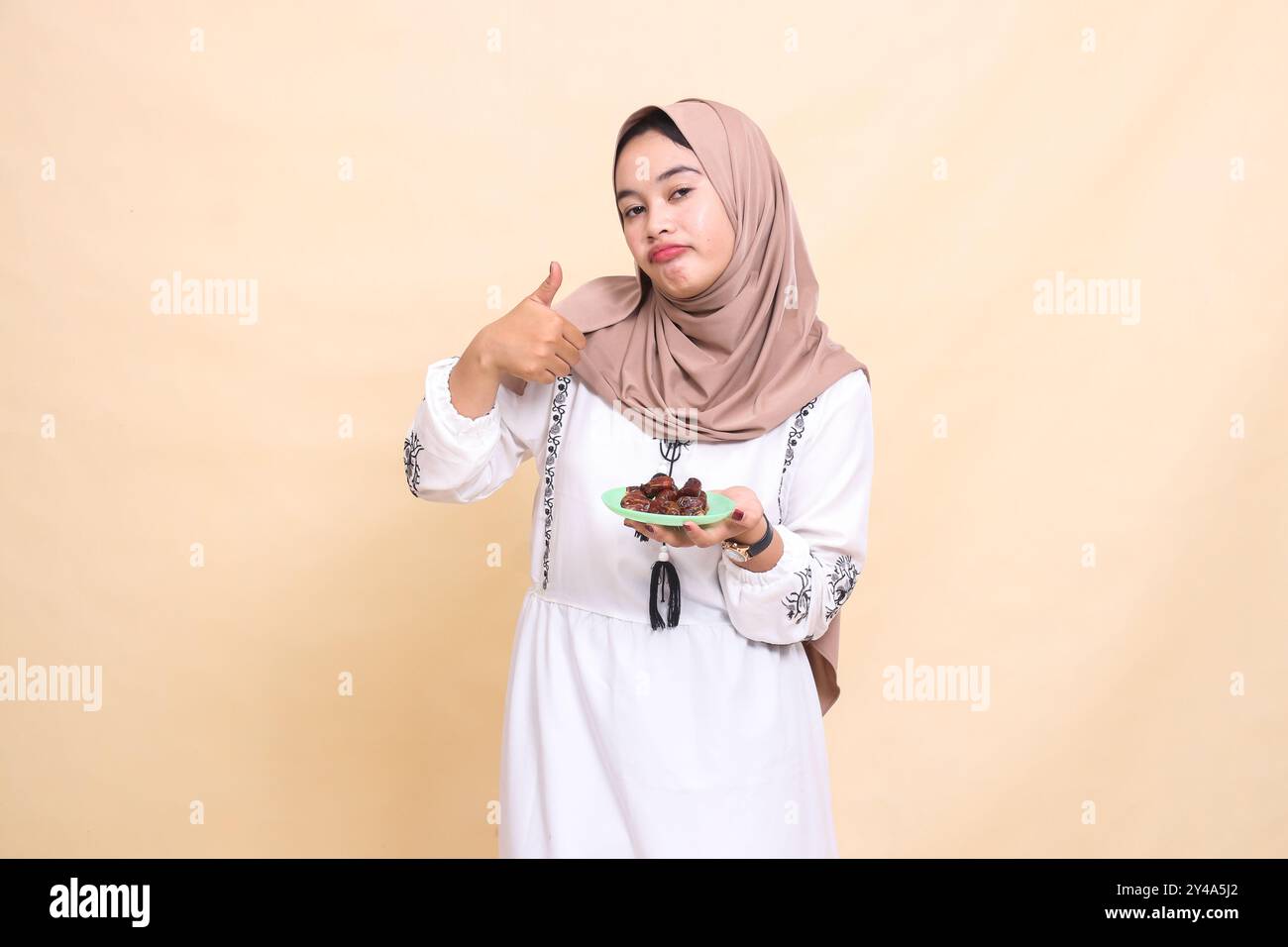 a beautiful indonesia Muslim woman in a hijab pouted with a thumbs up ...