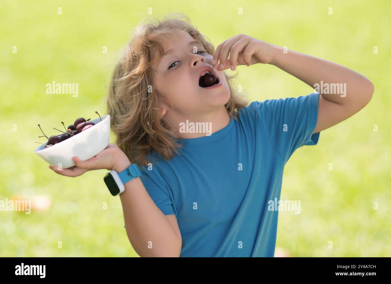 Cherry in kids mouth. Cute little boy eating cherries, making funny ...