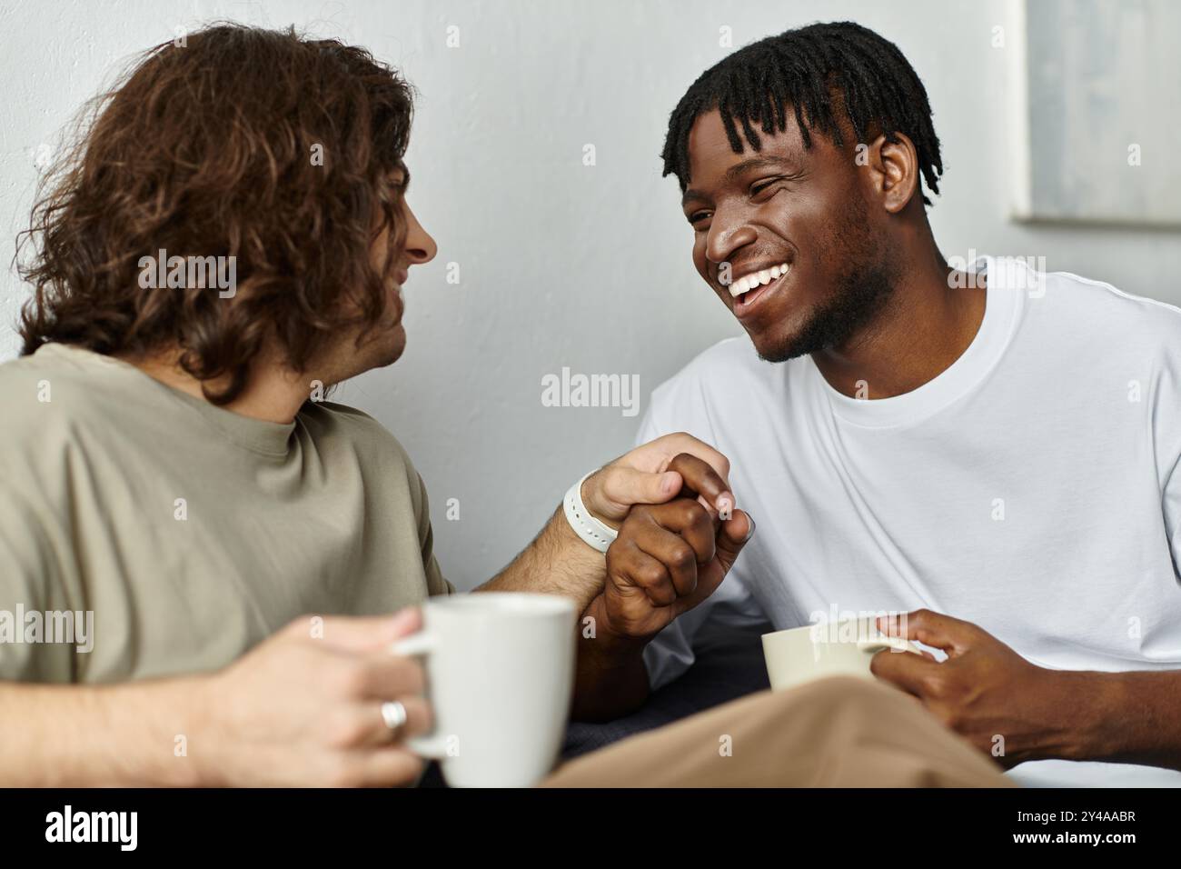 Two partners sit close, holding hands and sharing warm smiles over ...