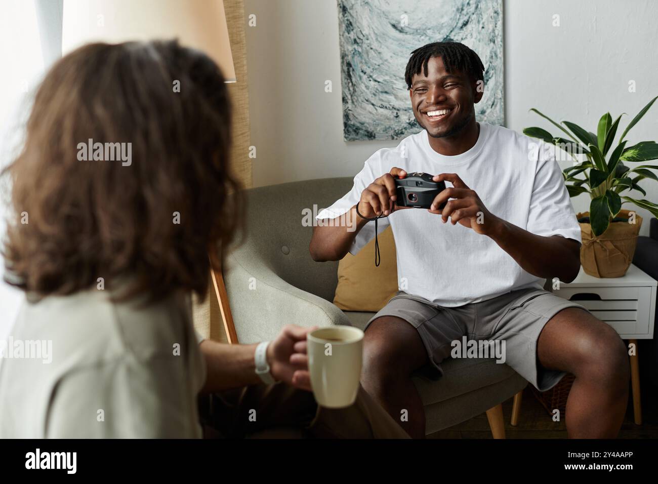 A couple shares laughter in a cozy space, playfully capturing their ...