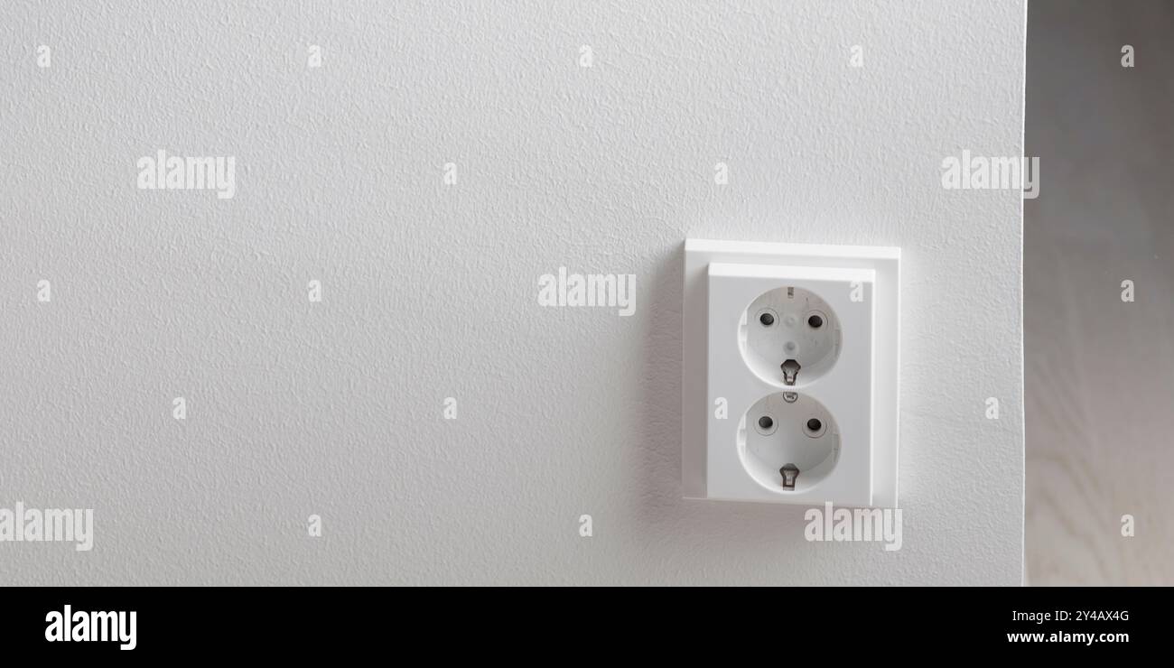 A close-up of a double electrical outlet mounted on a white wall ...
