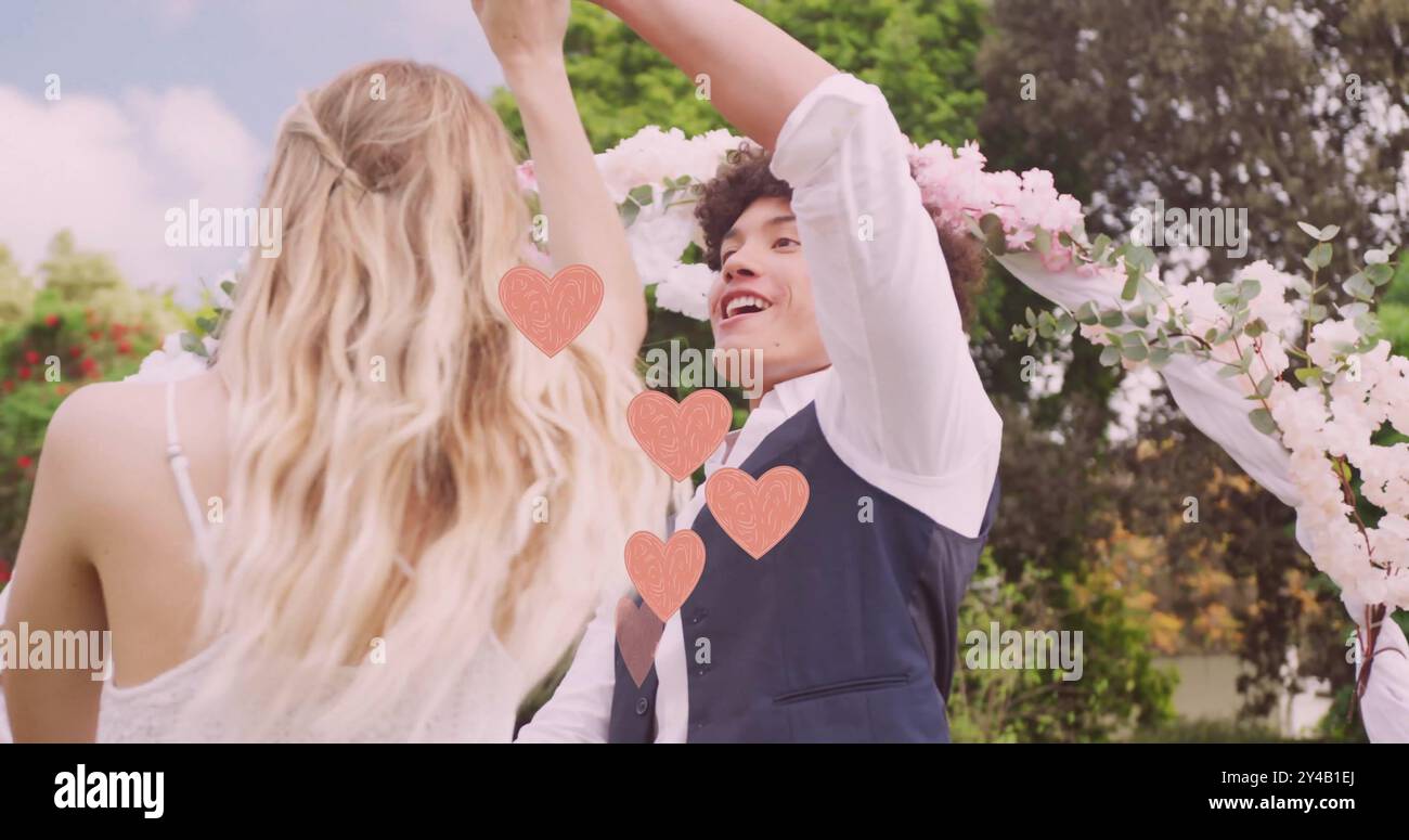 Image of pink hearts over happy diverse couple dancing in garden on ...