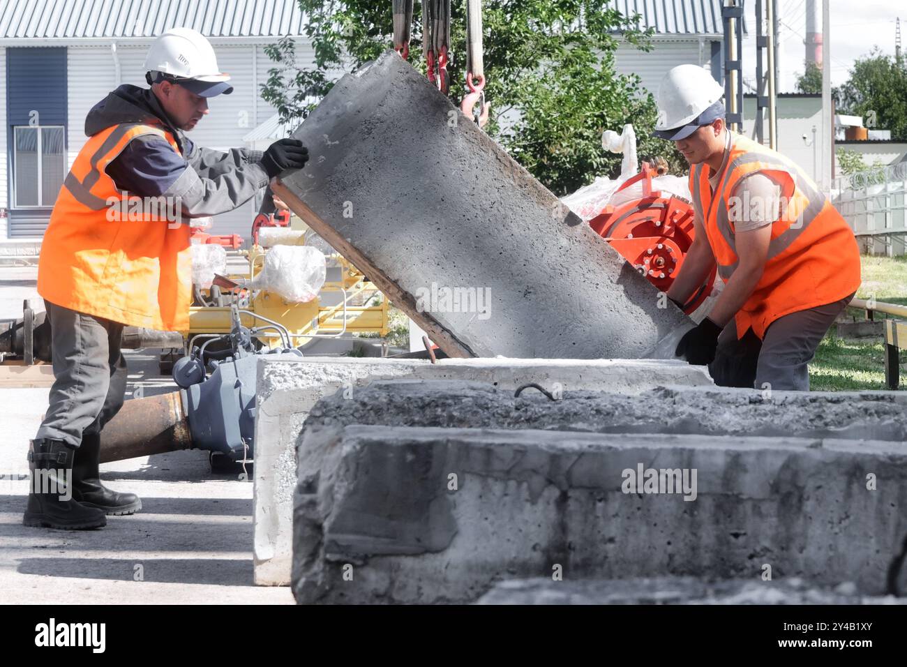 Two construction workers wearing safety gear collaboratively lifting ...
