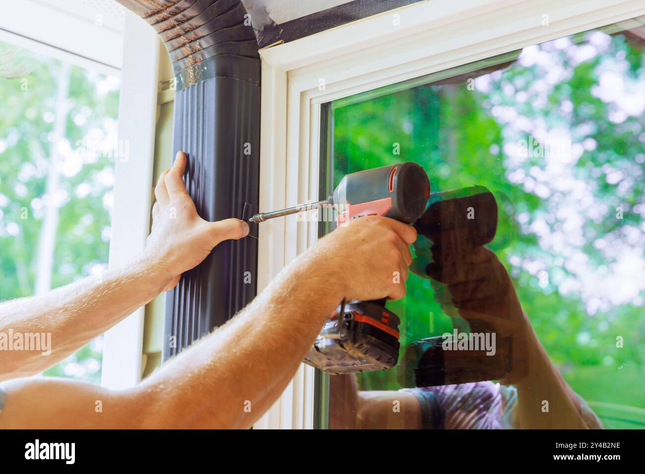 Handyman is assembling gutter channel that is attached to roof with ...