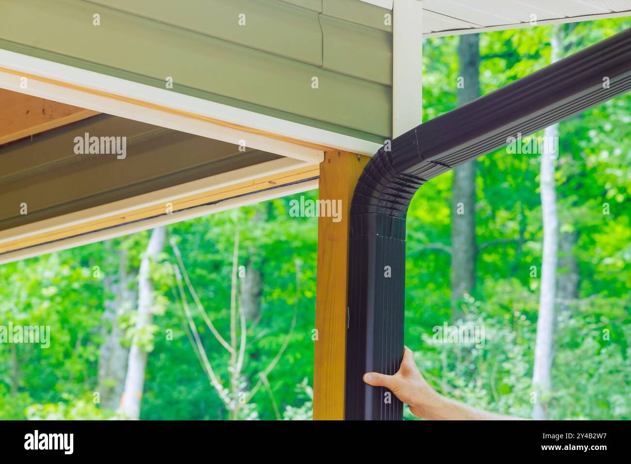 It is handyman who is assembling gutter channel on roof with help of ...