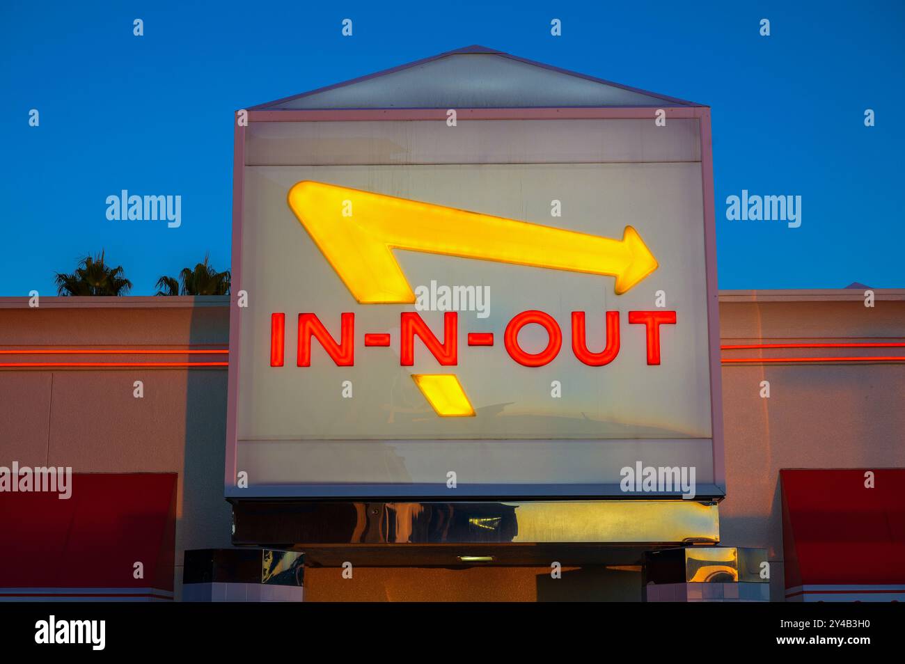 Illuminated In-N-Out Burger sign with a yellow arrow and red text at ...