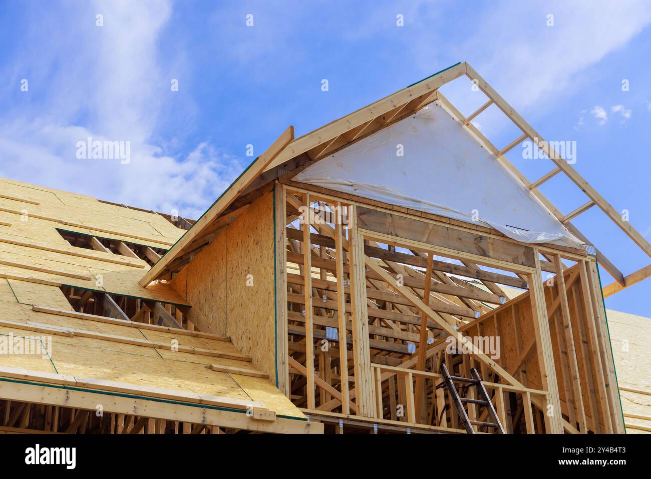 Assembling roof to house under construction by installing plywood on ...