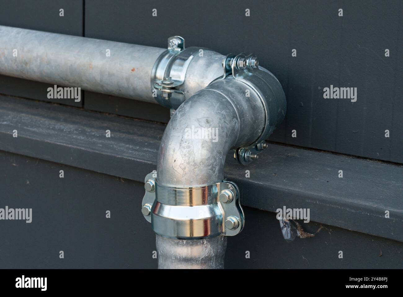 A close view of a metal plumbing pipe featuring a shiny elbow joint ...