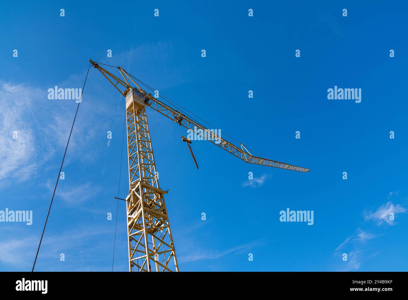 A tall construction crane stands against a clear blue sky, showcasing ...