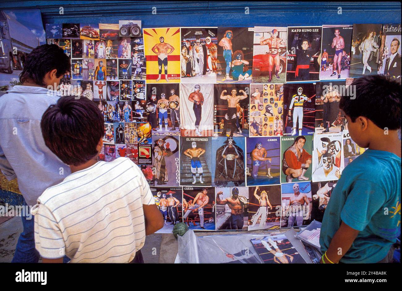 Mexico, Merida. Boys are looking at posters and cards of Mexican lucha ...
