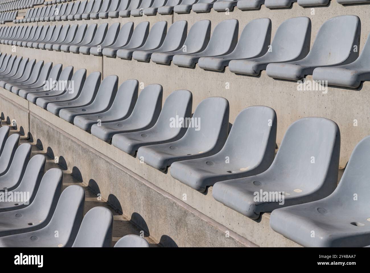 The rows of gray seats are arranged uniformly in a large, open stadium ...