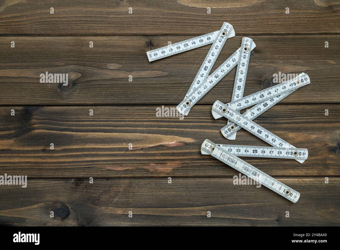 A folding ruler lying on an old wooden table of dark brown color. View ...