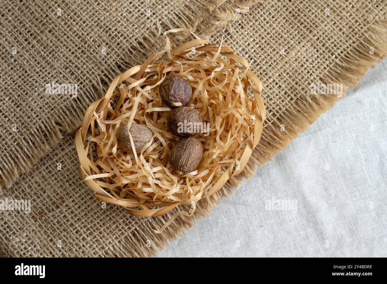 Nutmeg macro in tiny basket on rough linen textured background Top view ...
