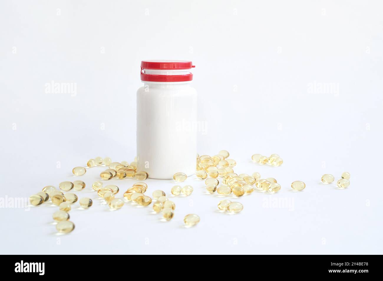 Clear gel capsules and white plastic bottle with red cap on white ...