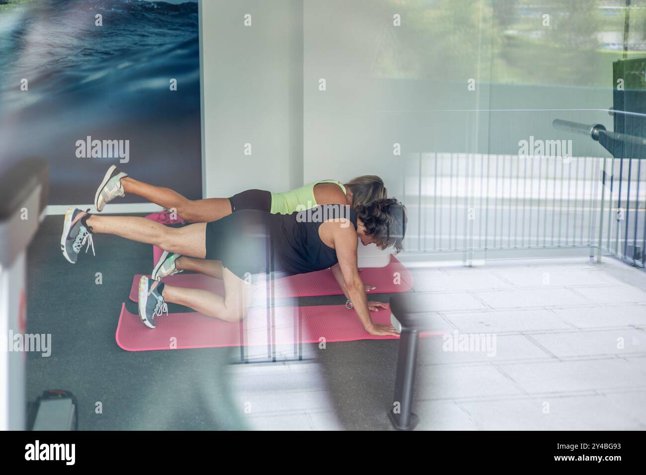 Two mature sporty women are performing leg exercises on yoga mats ...