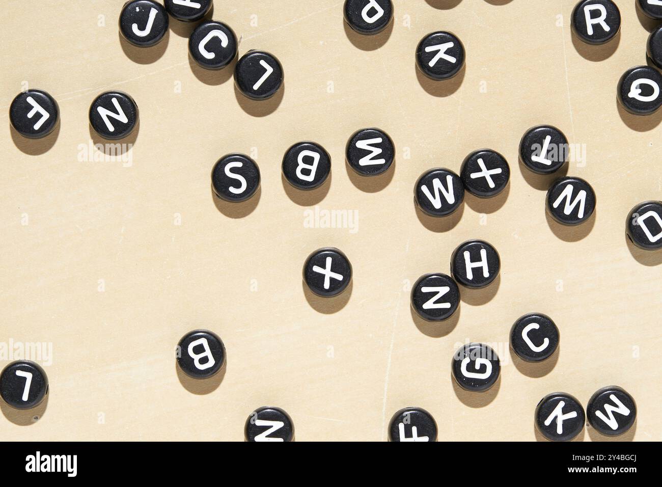 Scattered black alphabet letter beads on beige background for creative ...