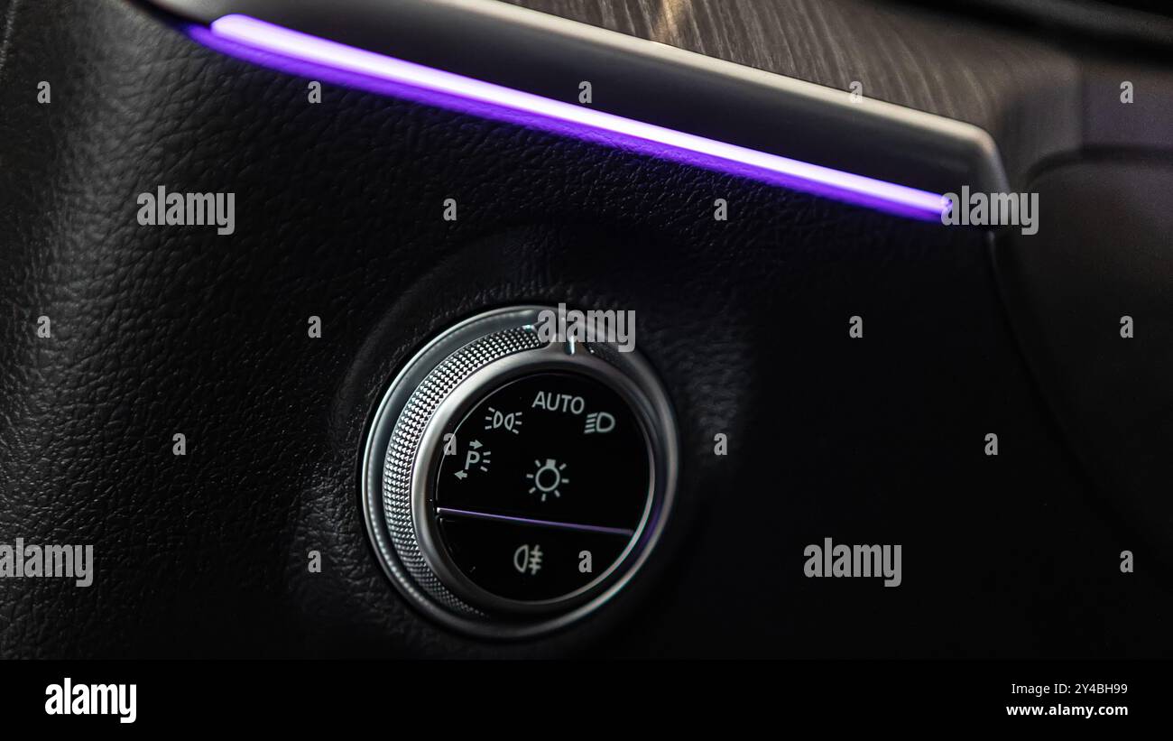 Close-up of a luxury car dashboard featuring a headlight control dial ...