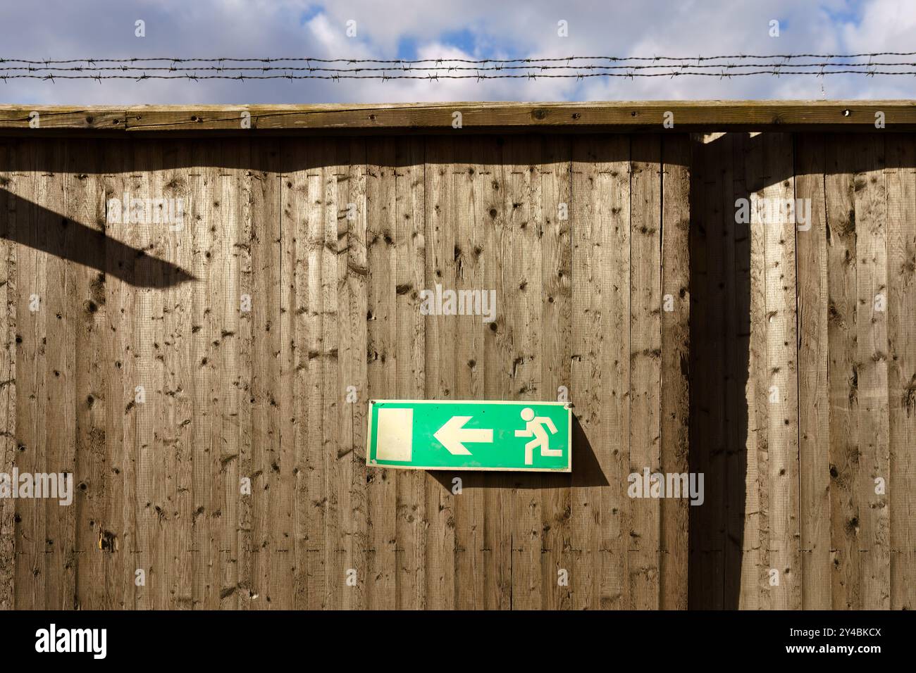 Green exit sign on wooden fence with barbed wire Stock Photo - Alamy