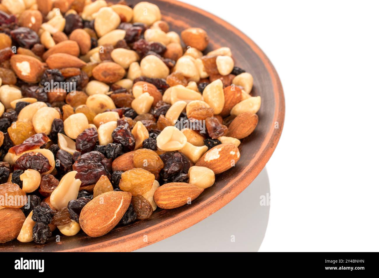 Nut mixture with dry berries on a clay plate, macro, isolated on white ...