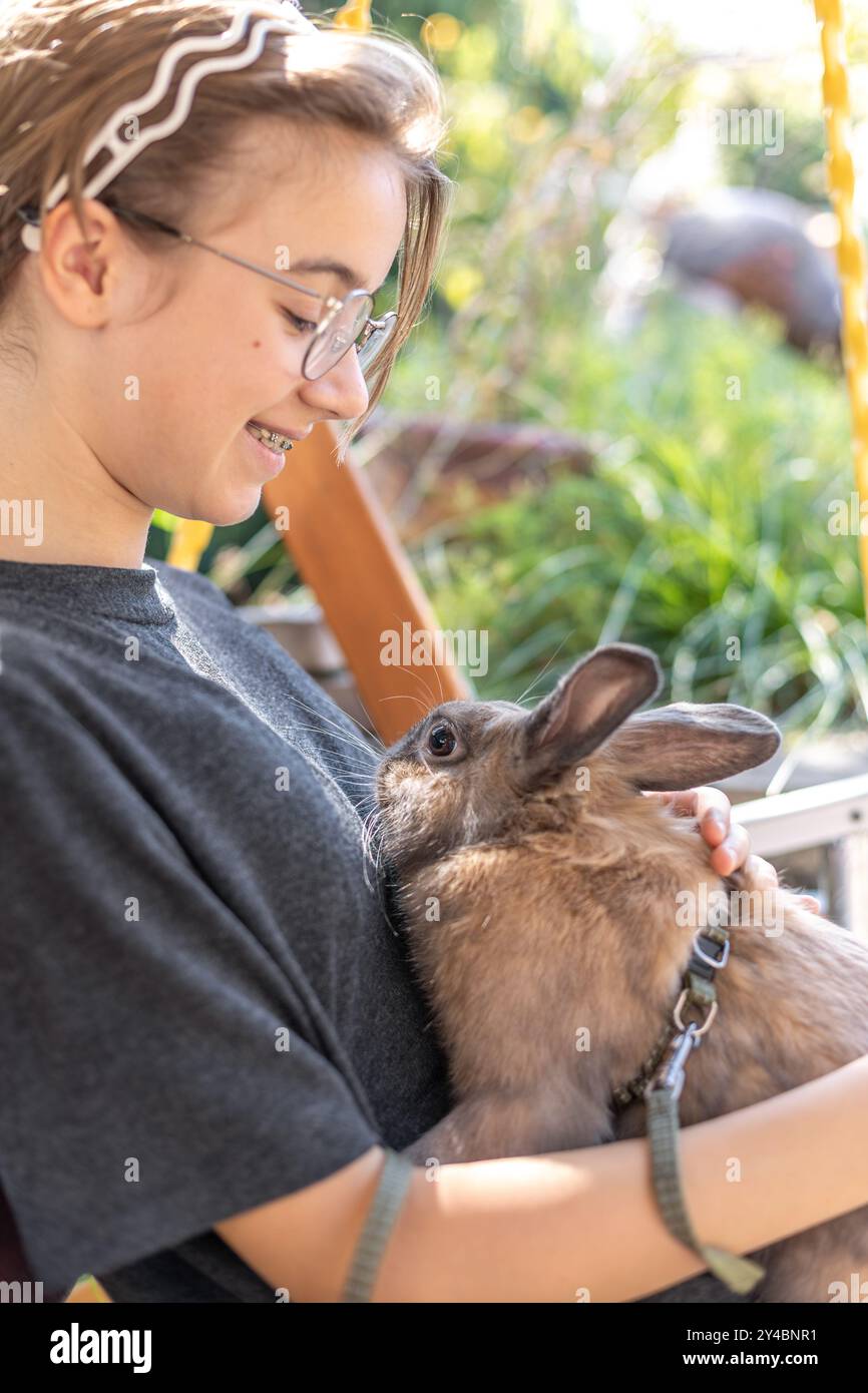 A girl plays with a domestic rabbit on the street. Pet concept Stock ...