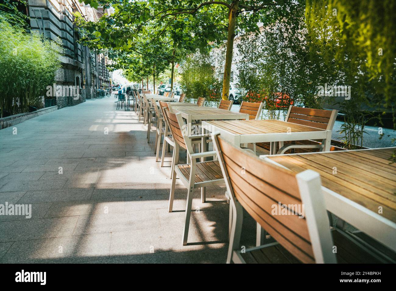 Street restaurants tables. Sidewalk among urban greenery Stock Photo ...